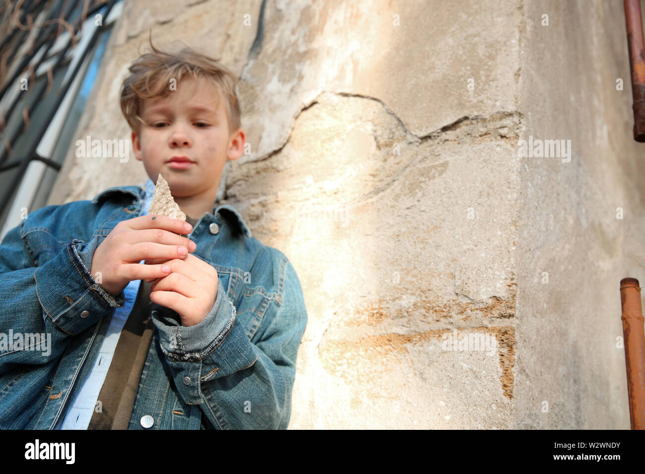 Homeless little boy eating bread outdoors Stock Photo - Alamy