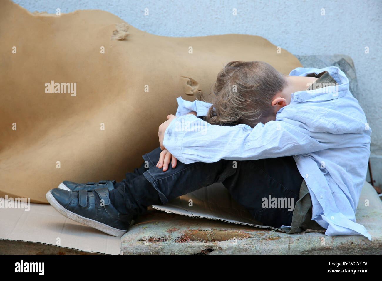 Homeless little boy sitting outdoors Stock Photo - Alamy