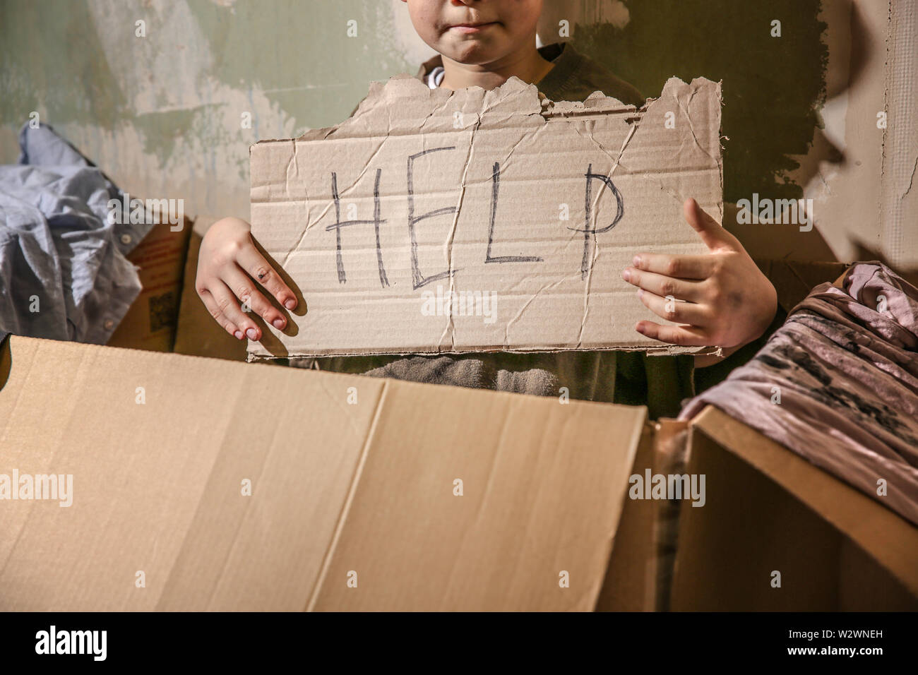 Homeless little boy begging for help indoors Stock Photo - Alamy