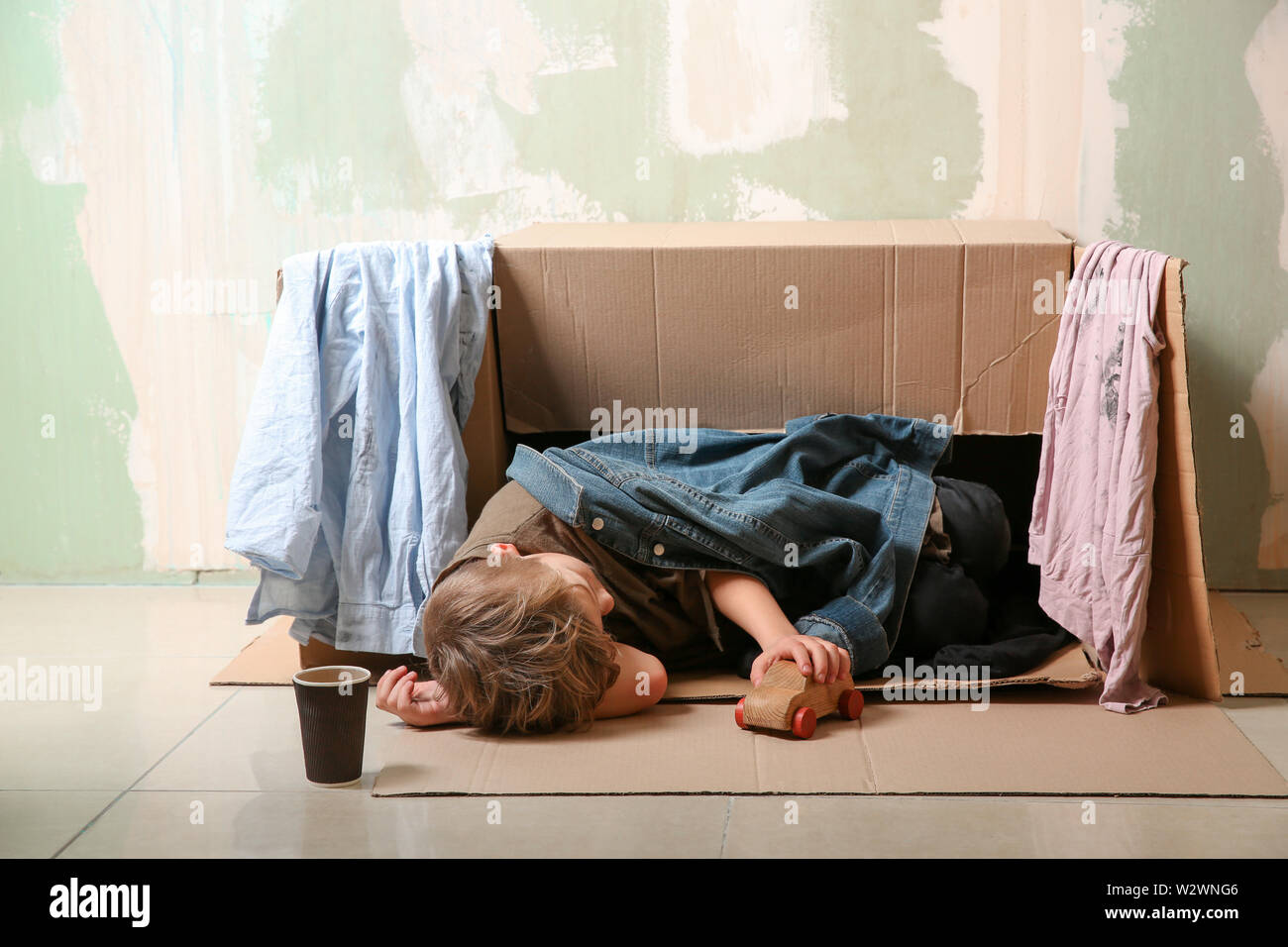 Homeless little boy with toy car lying in big box Stock Photo - Alamy