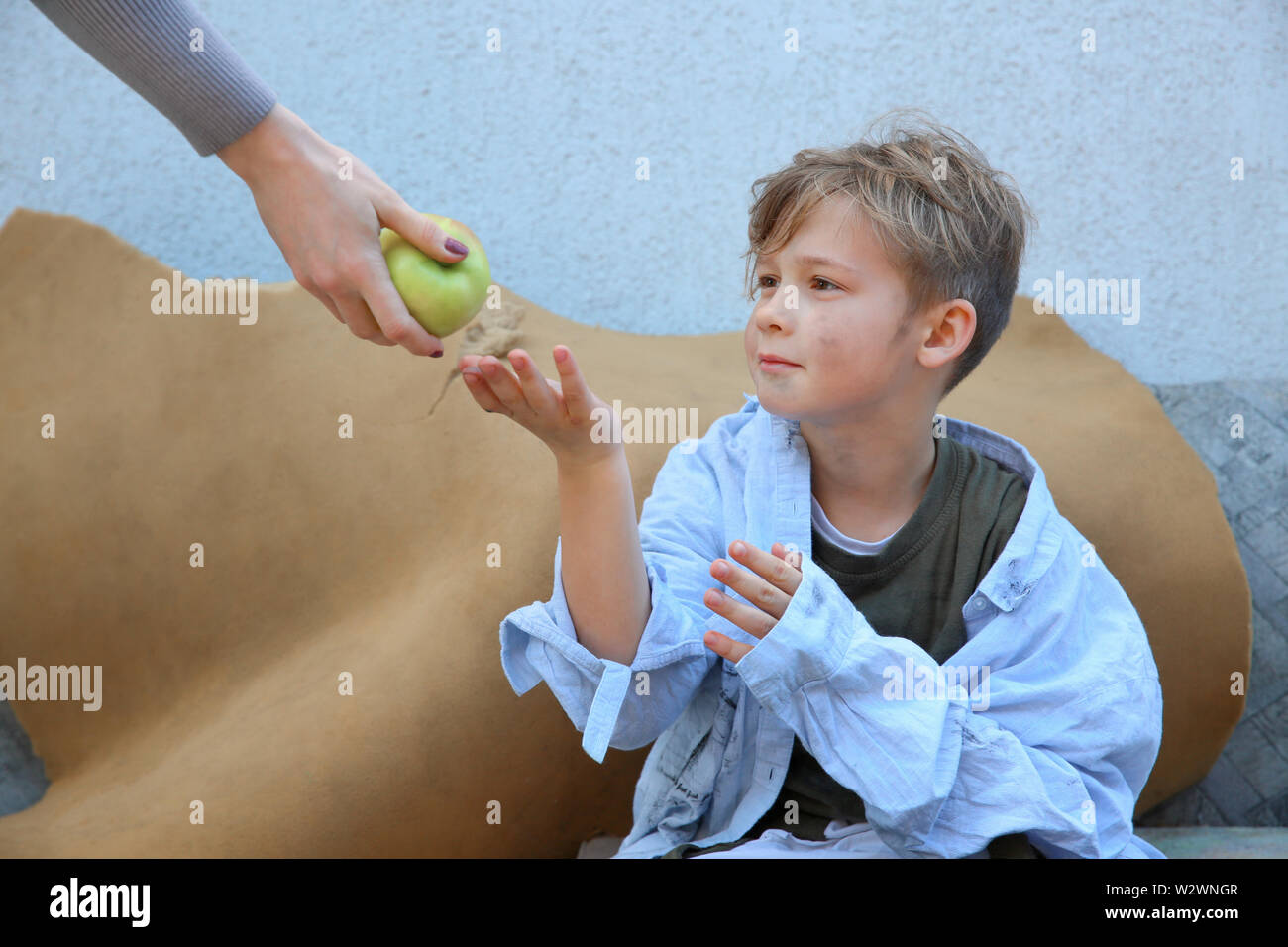 Woman giving food to homeless little boy outdoors Stock Photo - Alamy