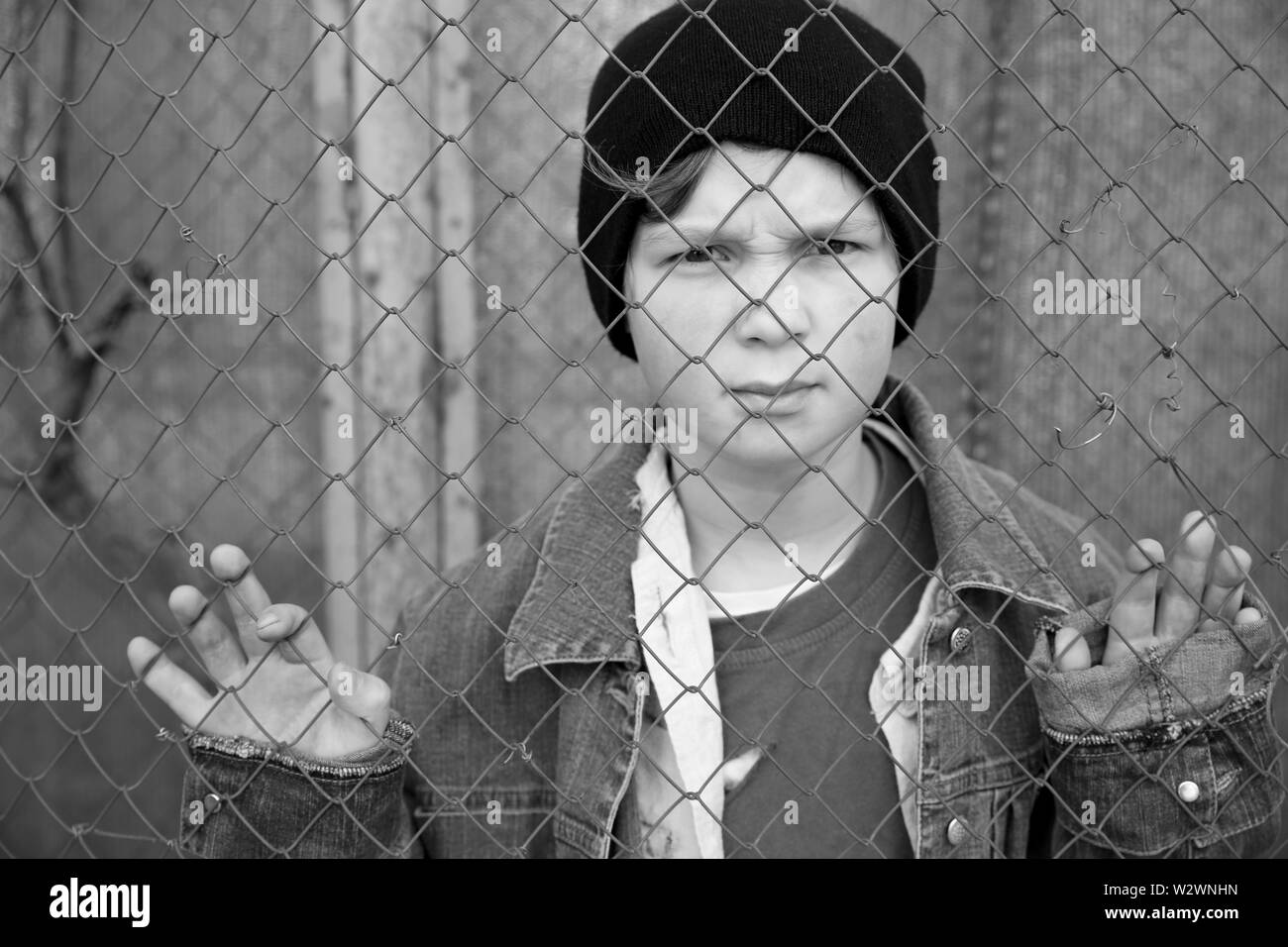 Homeless little boy standing behind mesh outdoors Stock Photo - Alamy