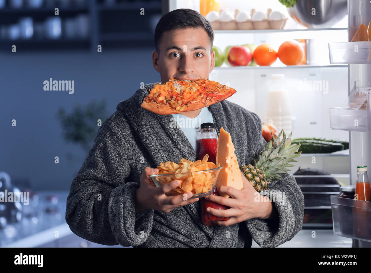 Afraid man caught in the act of choosing tasty food near refrigerator ...