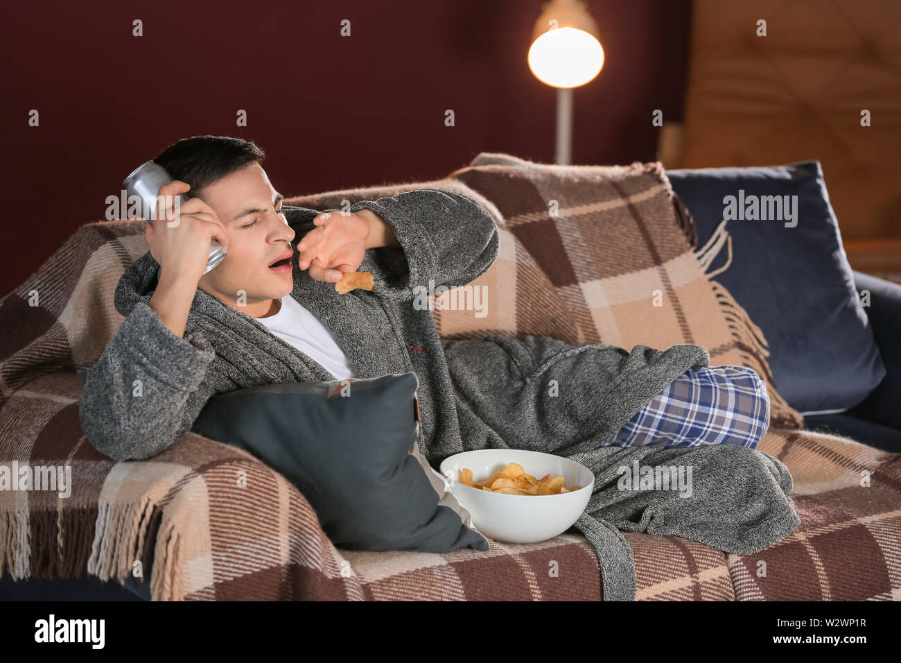 Tired young man eating unhealthy food at night Stock Photo - Alamy