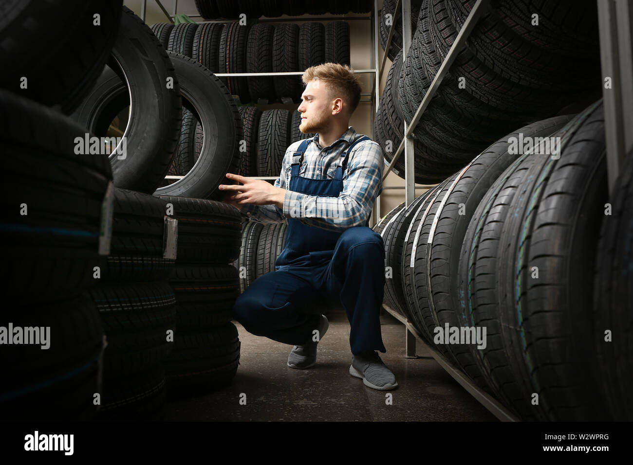 Male seller in car tire store Stock Photo - Alamy