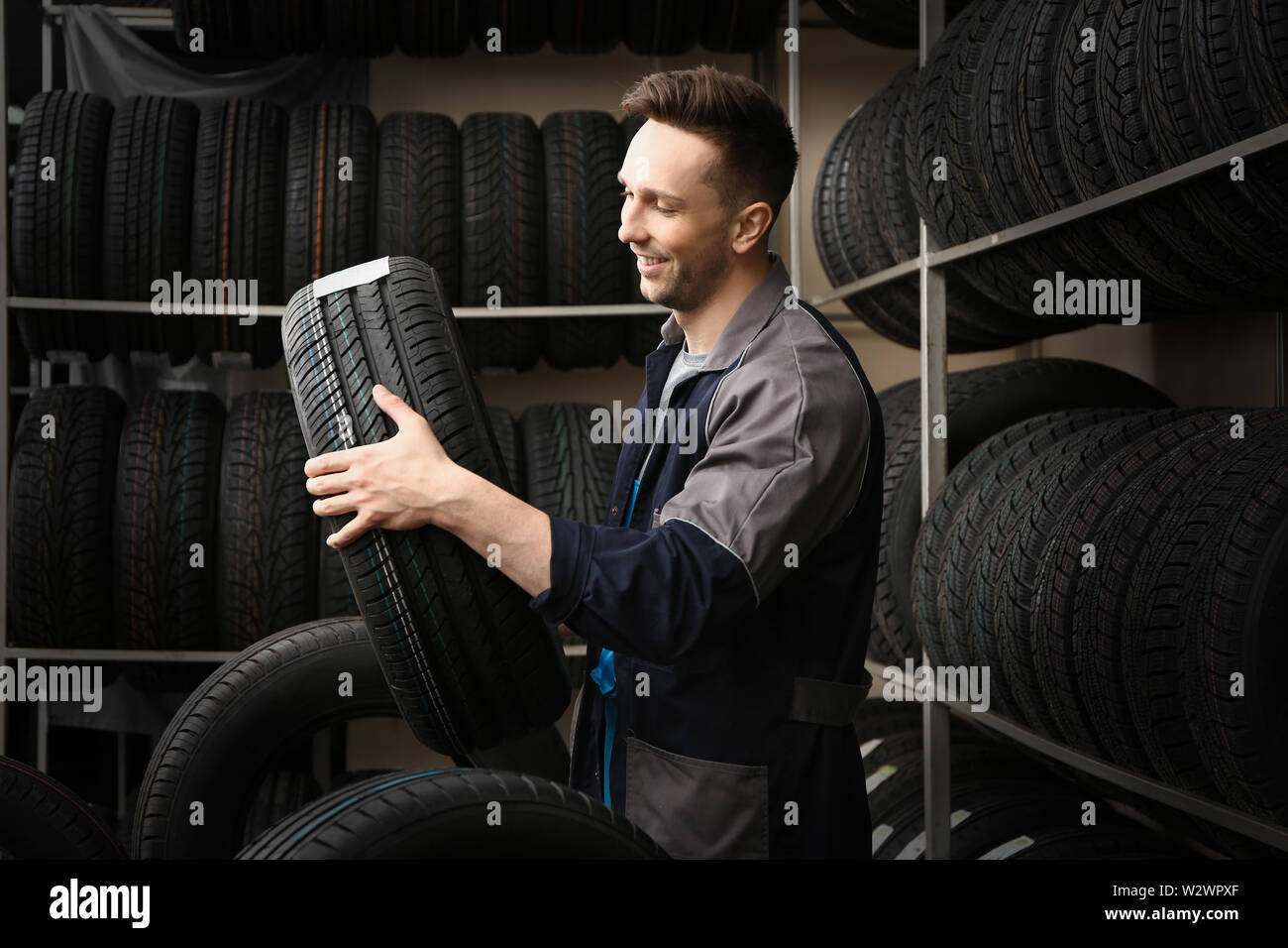 Male seller in car tire store Stock Photo - Alamy