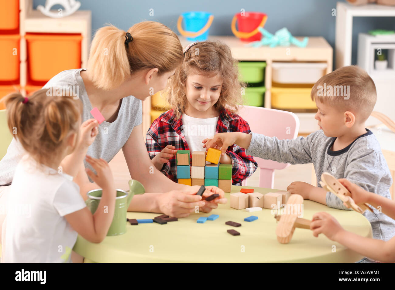 Nursery teacher with cute little children in kindergarten Stock Photo ...