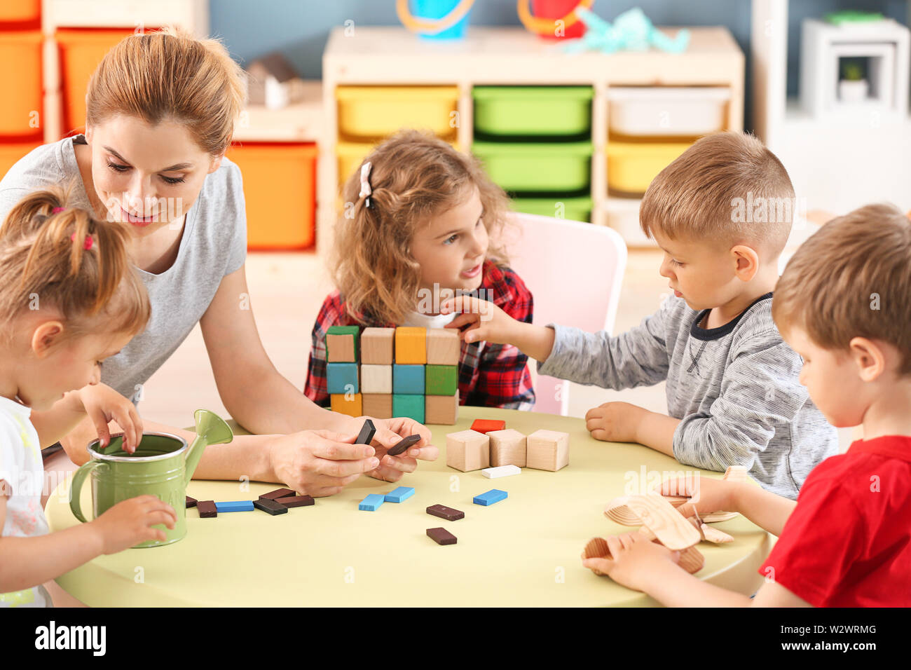 Nursery teacher with cute little children in kindergarten Stock Photo ...