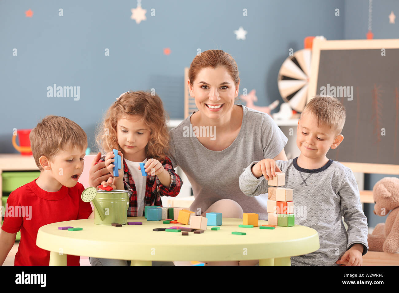 Nursery teacher with cute little children in kindergarten Stock Photo ...