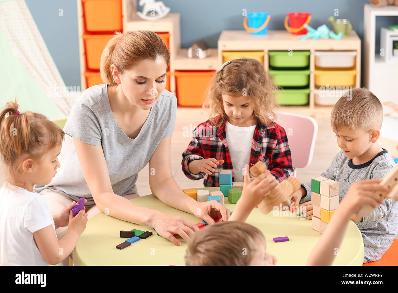 Nursery teacher with cute little children in kindergarten Stock Photo ...