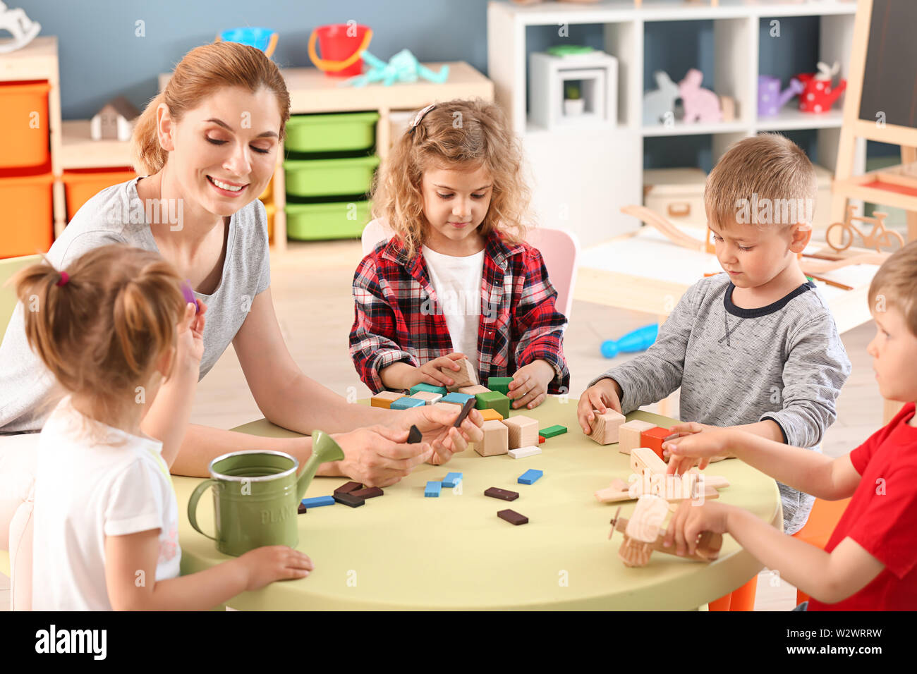 Nursery teacher with cute little children in kindergarten Stock Photo ...