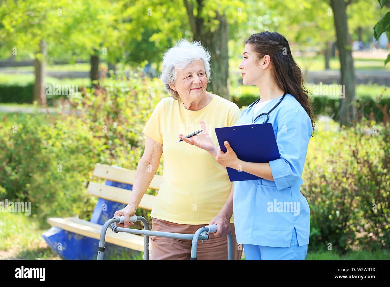 Caregiver walking with senior woman in park Stock Photo - Alamy