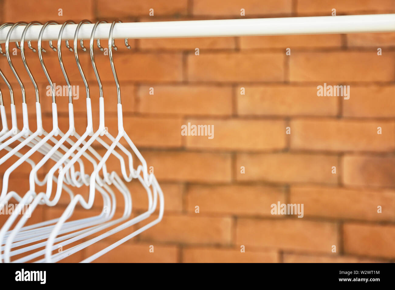 Rack with clothes hangers against brick wall Stock Photo - Alamy
