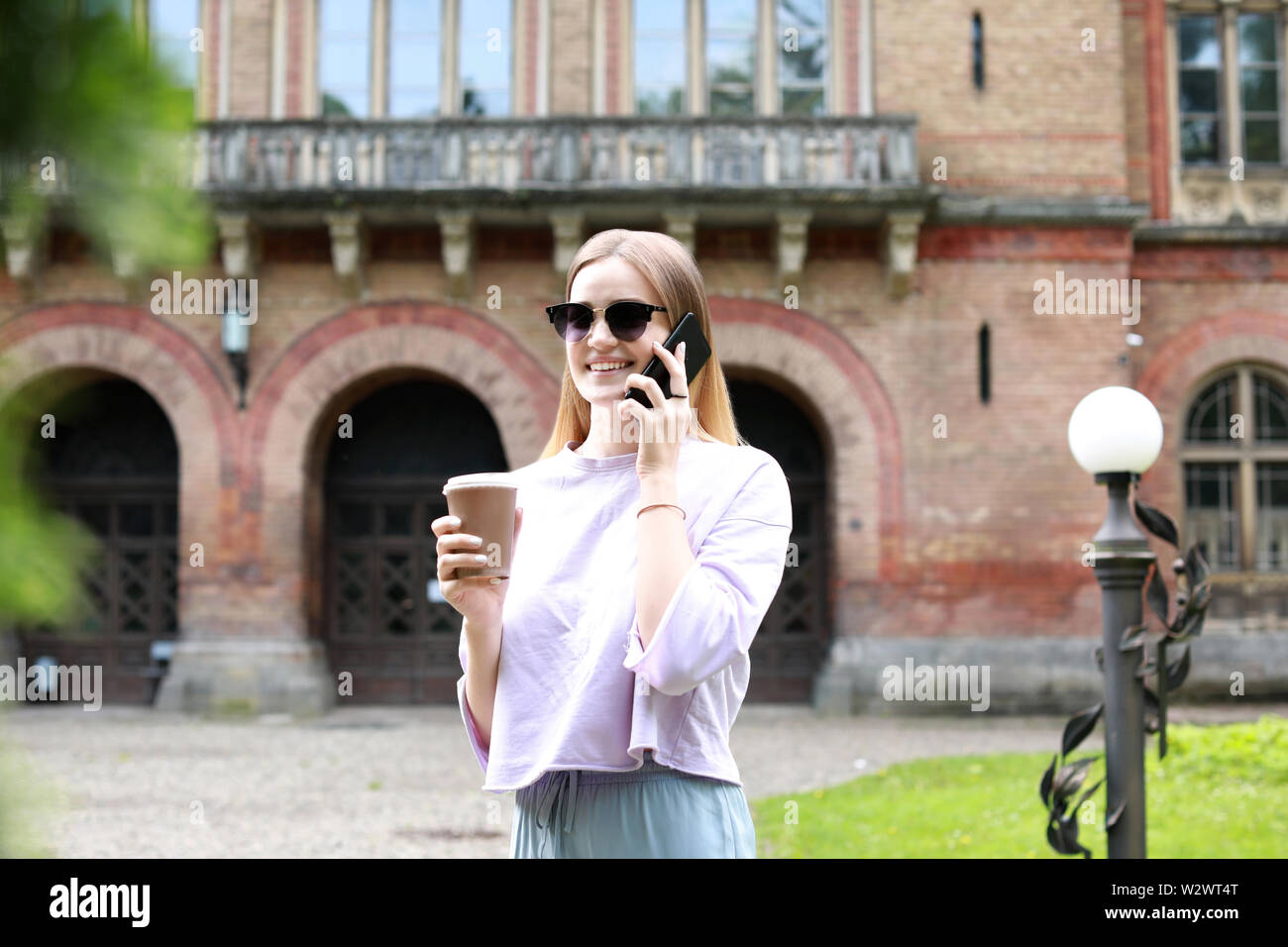 Female tourist talking by mobile phone near beautiful old building ...