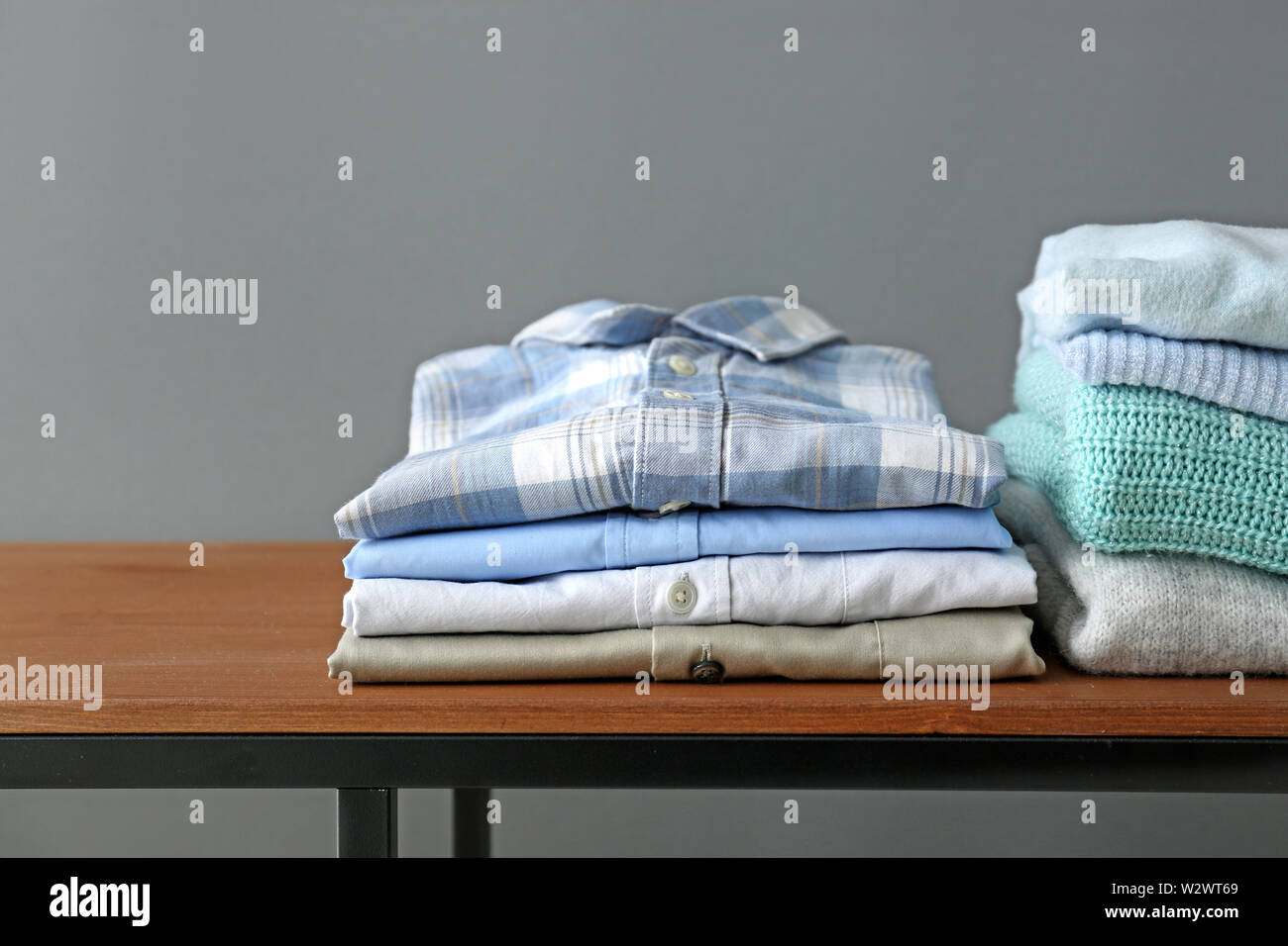 Stacked clothes on table against grey background Stock Photo - Alamy