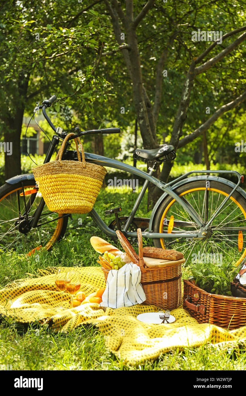 Bicycle and wicker baskets with tasty food and drink for romantic ...