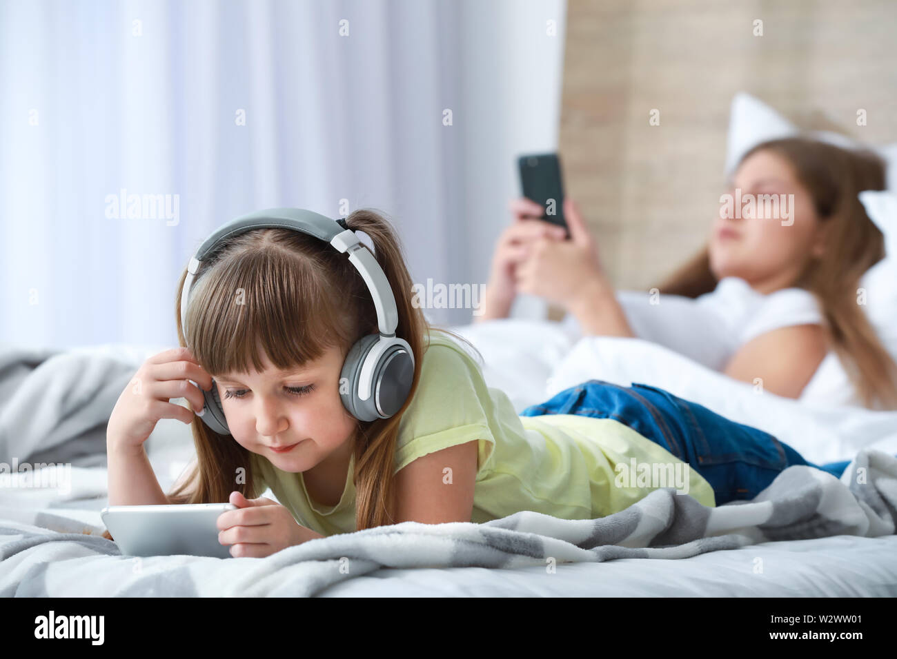Little girl with addiction to modern technologies lying with mobile ...