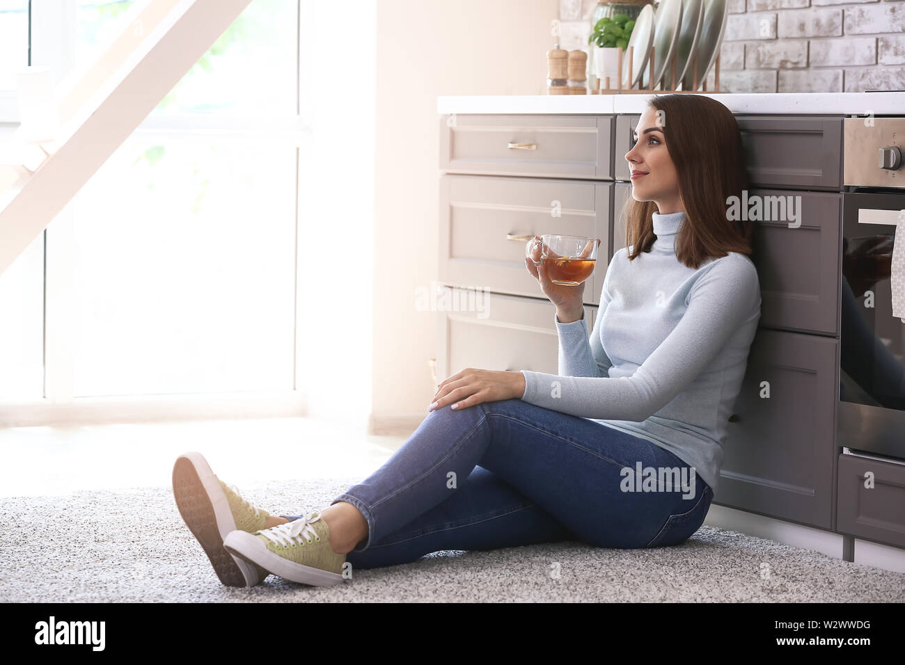Beautiful young woman drinking tea in kitchen Stock Photo - Alamy