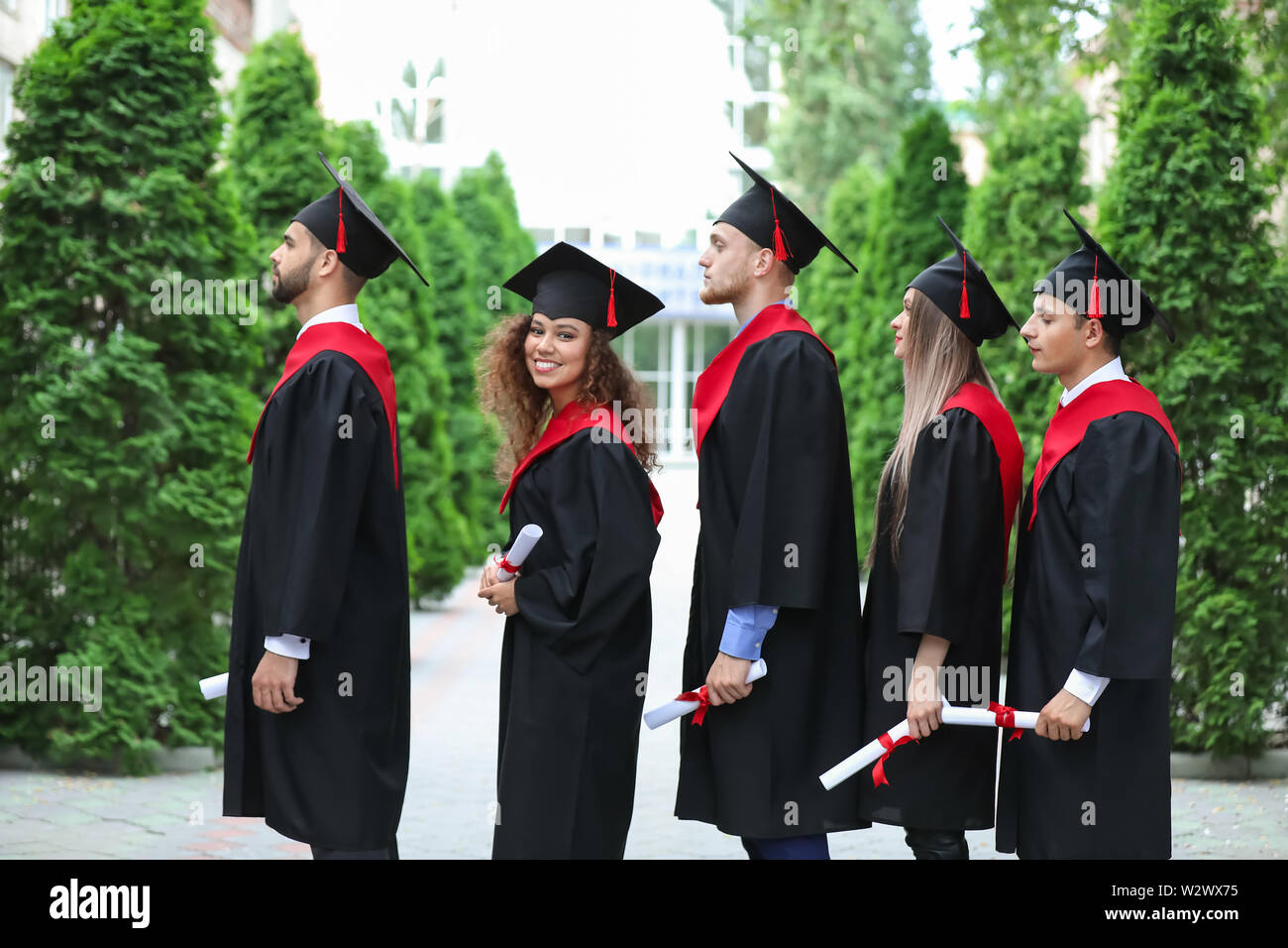 Happy students in bachelor robes outdoors Stock Photo - Alamy