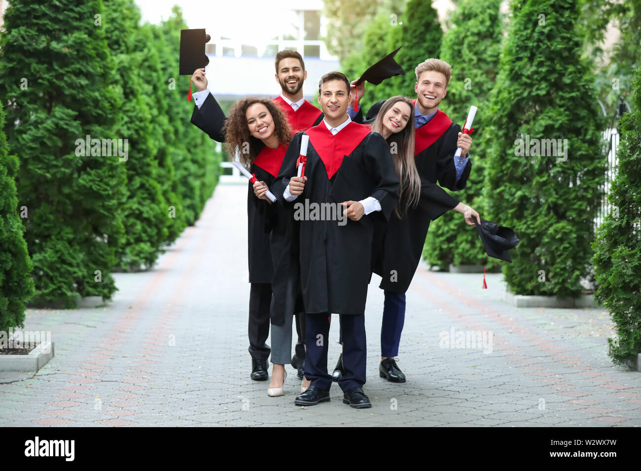 Happy students in bachelor robes outdoors Stock Photo - Alamy