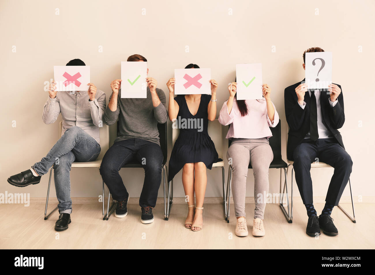 Young people holding paper sheets with different marks while sitting on ...