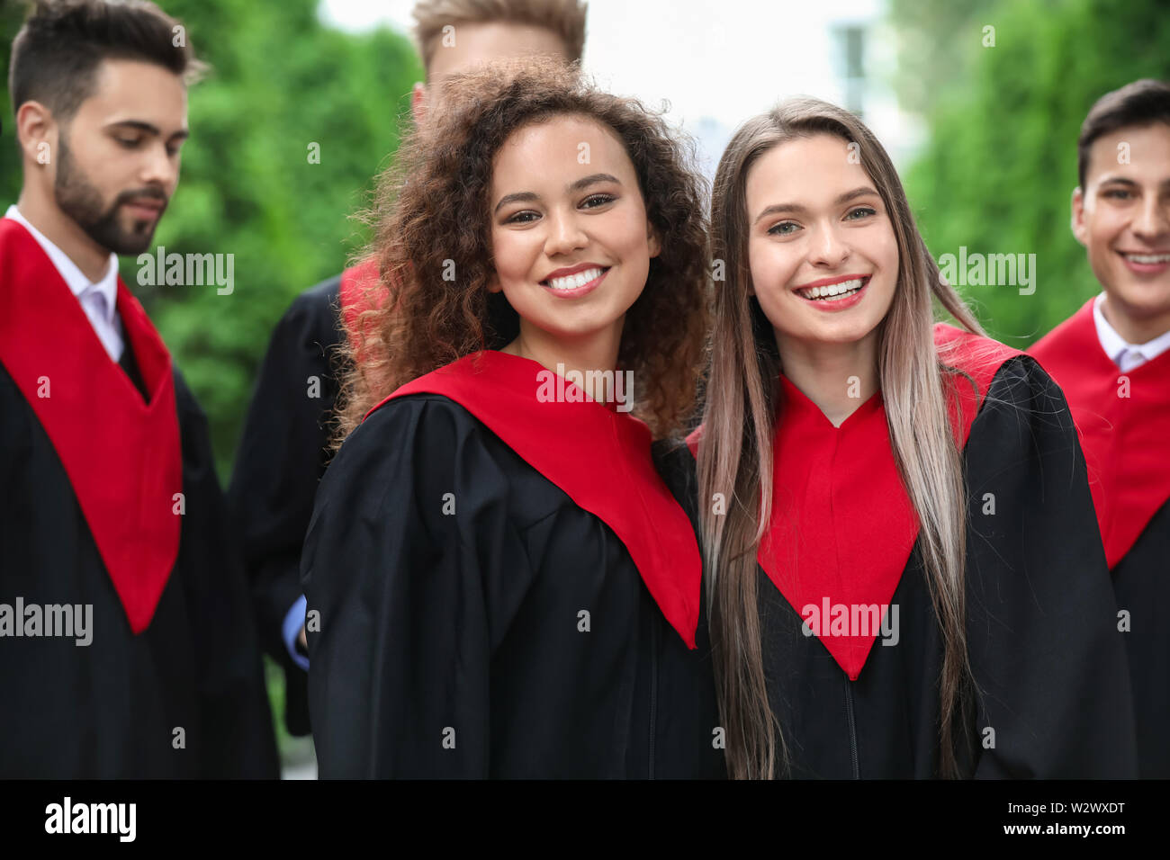 Happy students in bachelor robes outdoors Stock Photo - Alamy