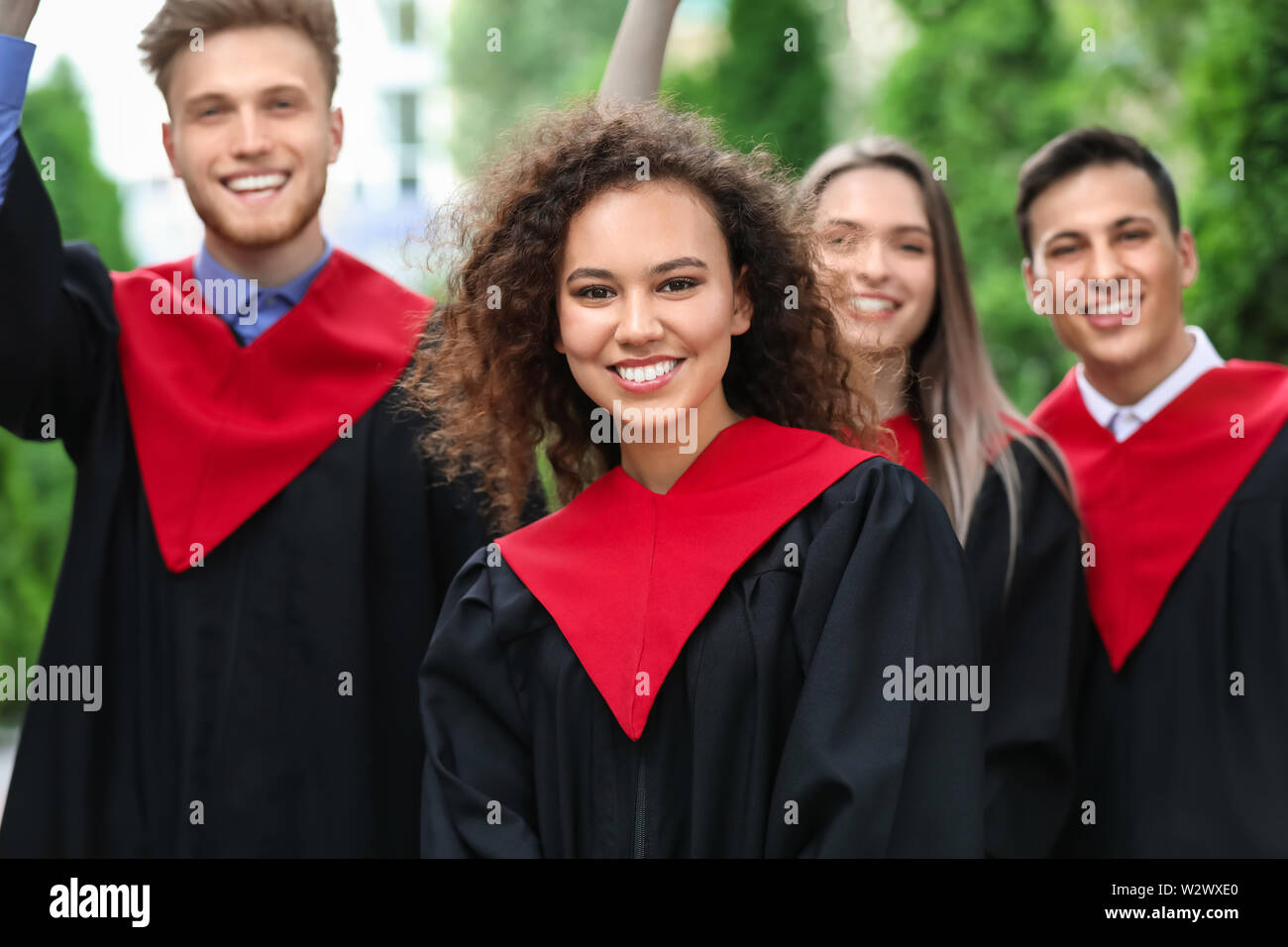 Happy students in bachelor robes outdoors Stock Photo - Alamy