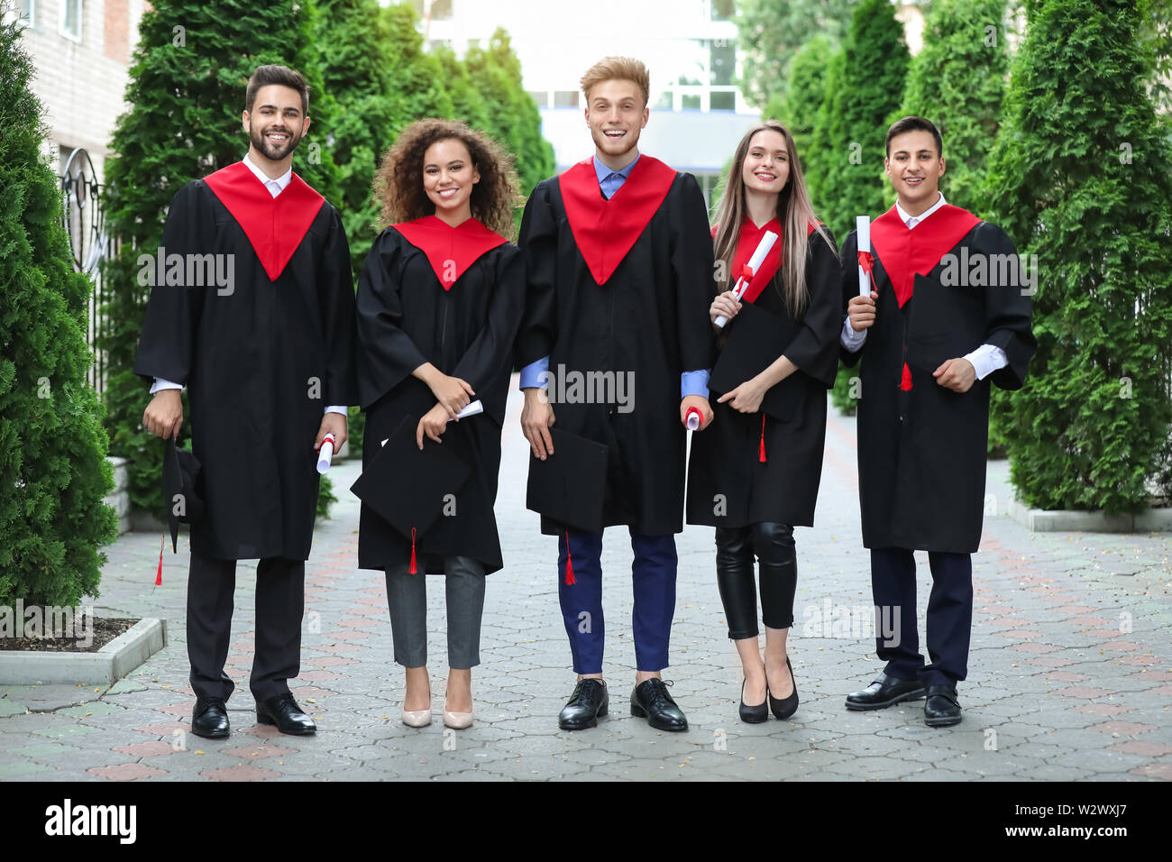Happy students in bachelor robes outdoors Stock Photo - Alamy