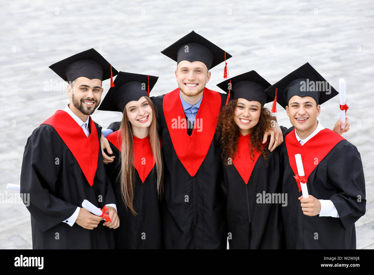 Happy students in bachelor robes outdoors Stock Photo - Alamy