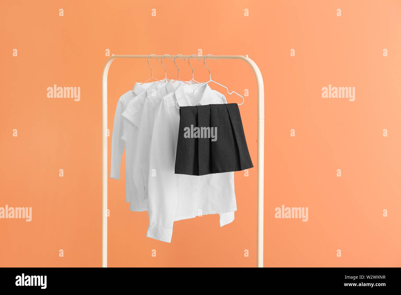 Stylish school uniform hanging on rack against color background Stock ...
