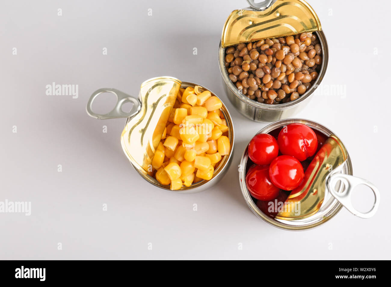 Tin cans with different food on light background Stock Photo - Alamy
