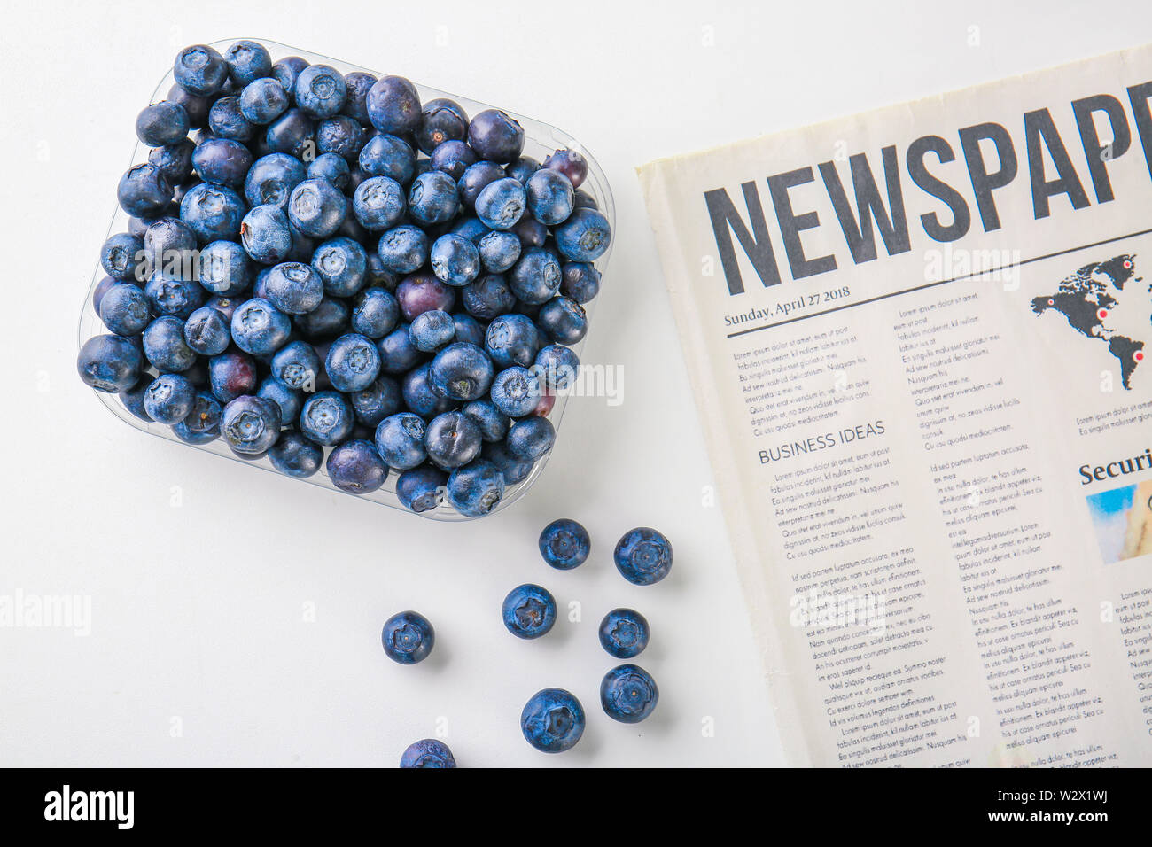 Bowl with ripe blueberry and newspaper on white background Stock Photo - Alamy