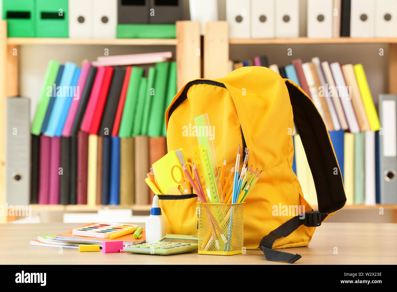 School backpack with stationery on table in classroom Stock Photo - Alamy