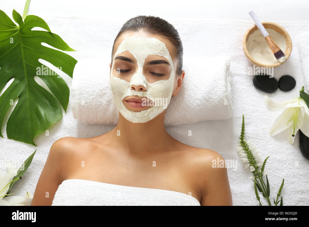Beautiful young woman with facial mask relaxing in spa salon Stock ...