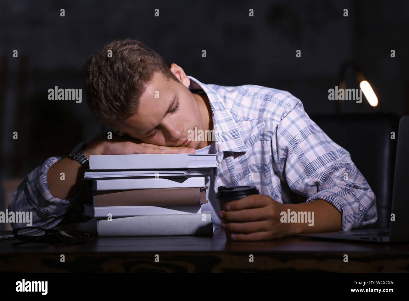 Tired male student sleeping at table instead of preparing for exam in ...