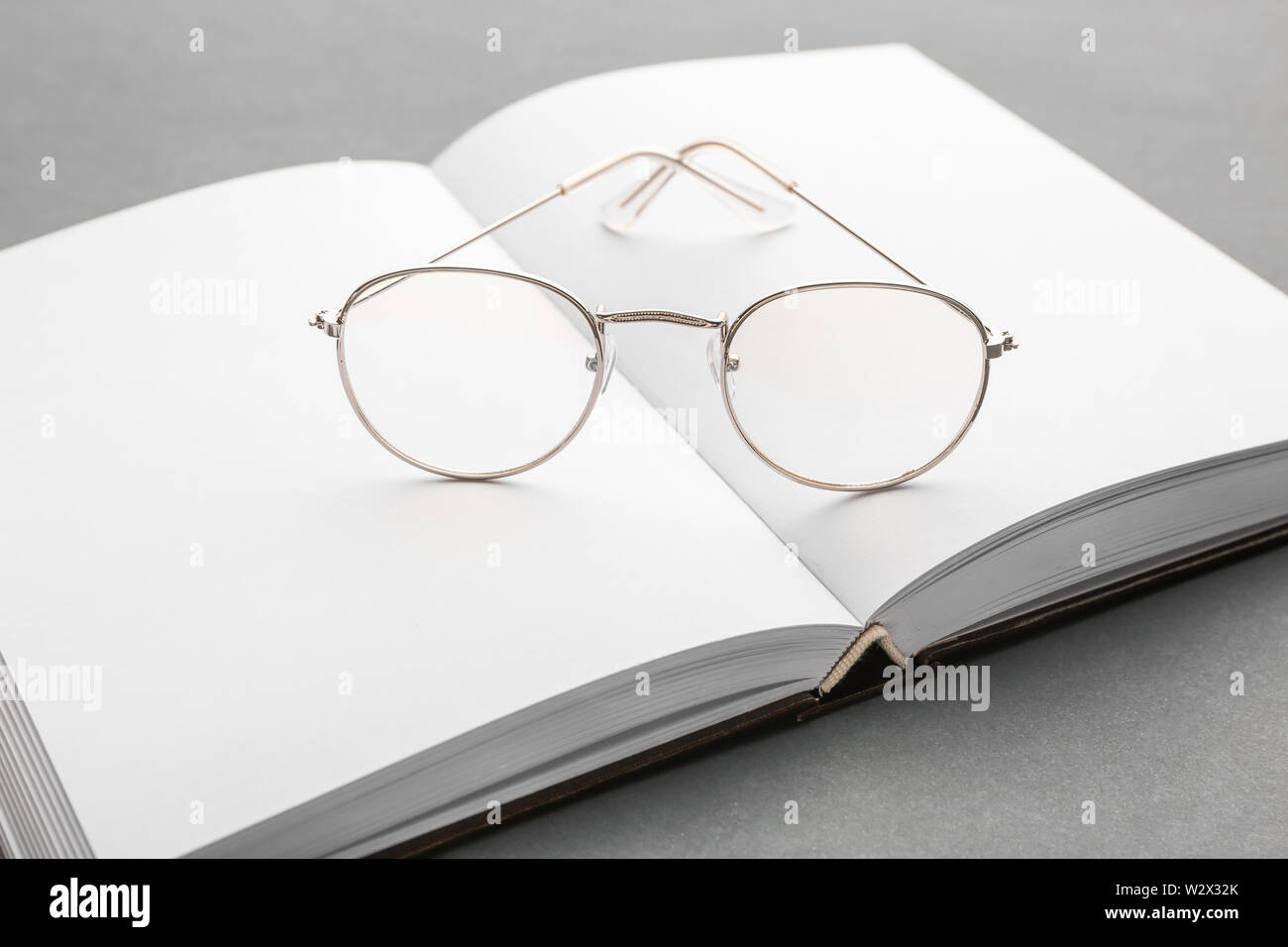 Open book with eyeglasses on grey background Stock Photo - Alamy