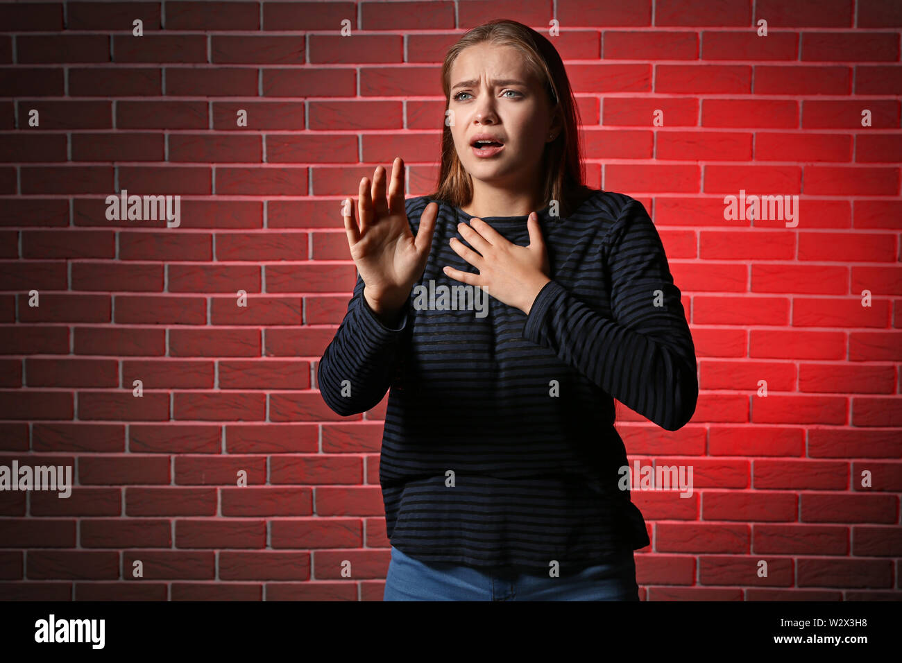 Woman having panic attack against brick wall Stock Photo - Alamy