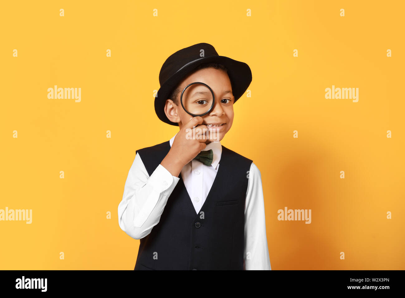 Little African-American detective with magnifier on color background ...