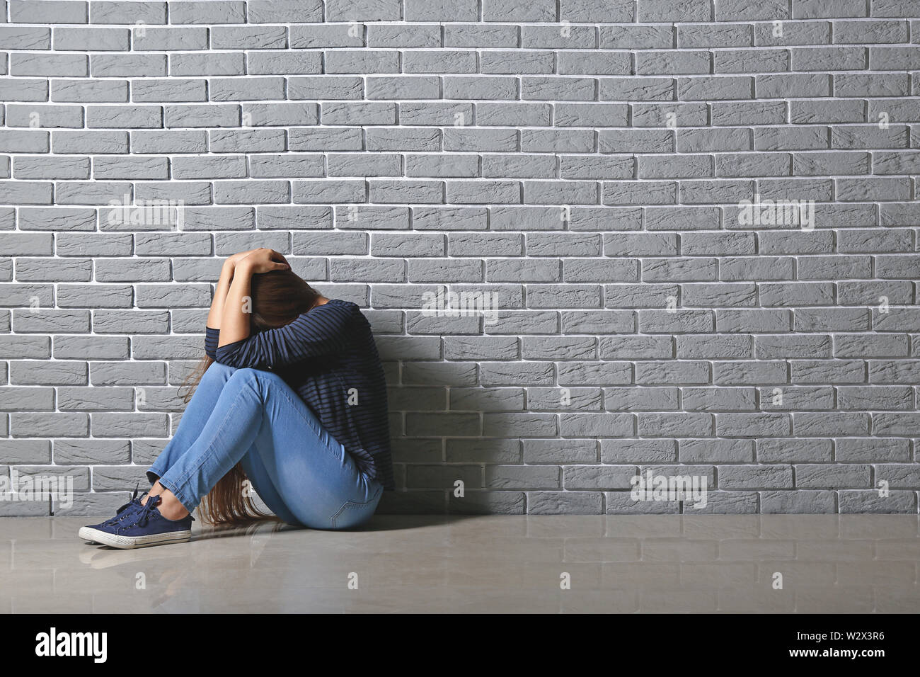 Woman having panic attack while sitting near brick wall Stock Photo - Alamy