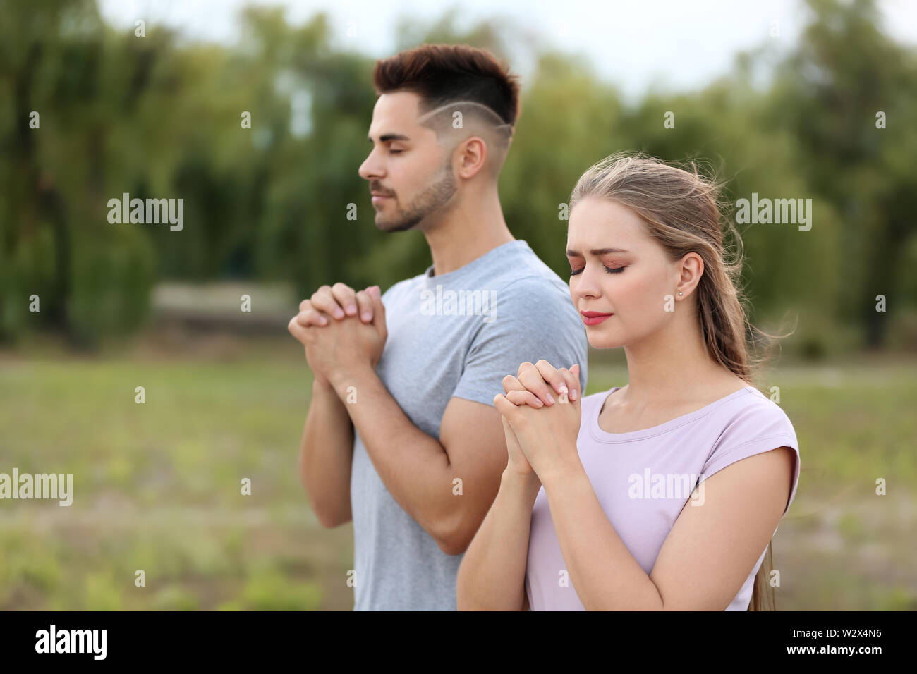 Young couple praying to God outdoors Stock Photo - Alamy