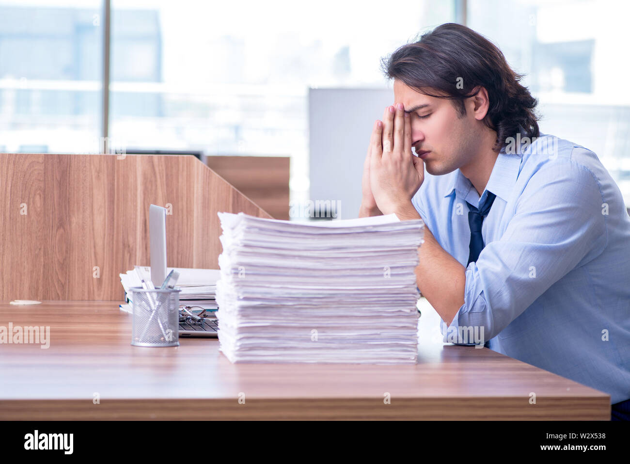 The young employee unhappy with excessive work Stock Photo - Alamy
