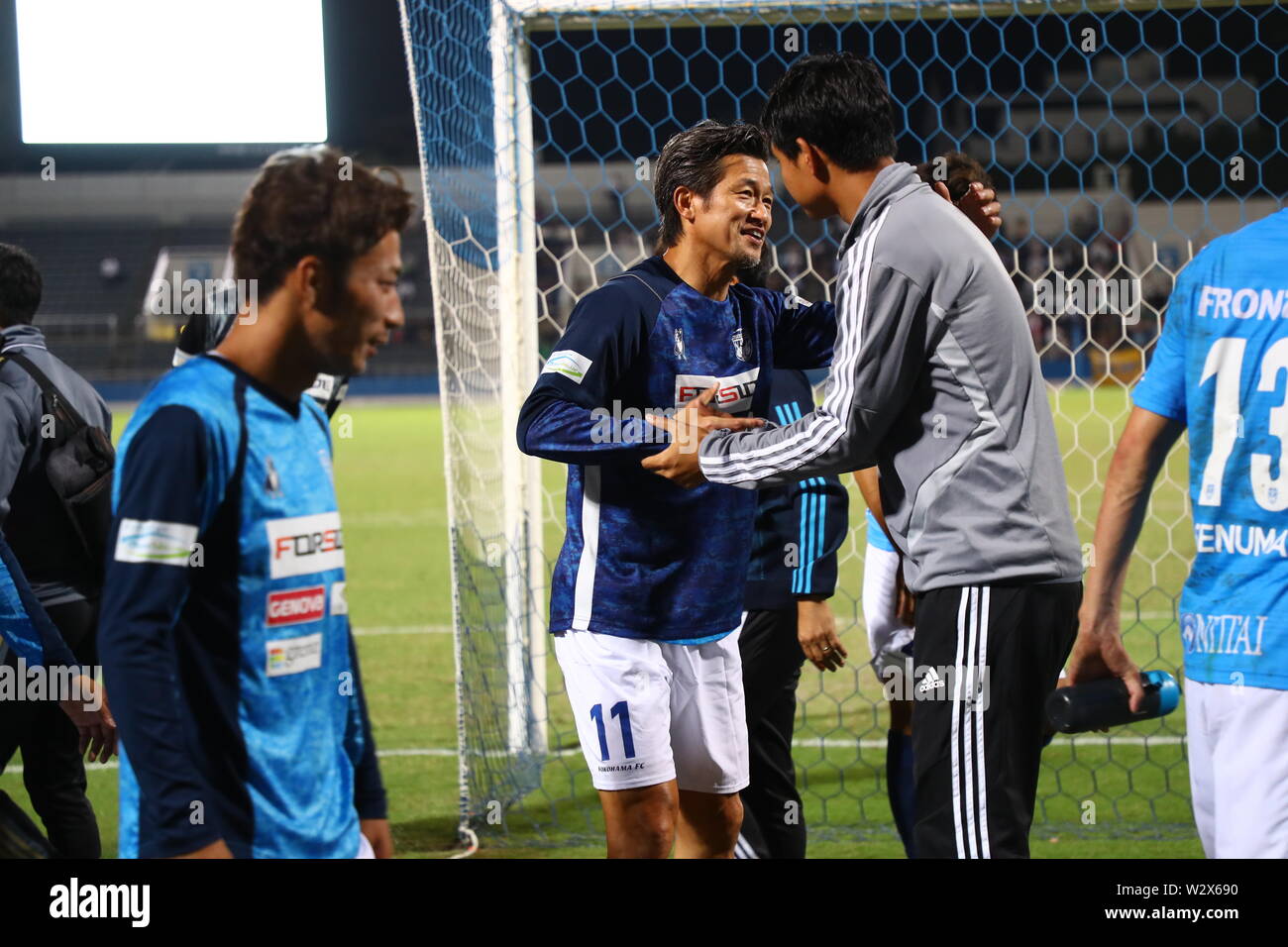 Yokohama FC's Kazuyoshi Miura shakes hands with Sendai University coach Sota Hirayama after the ...