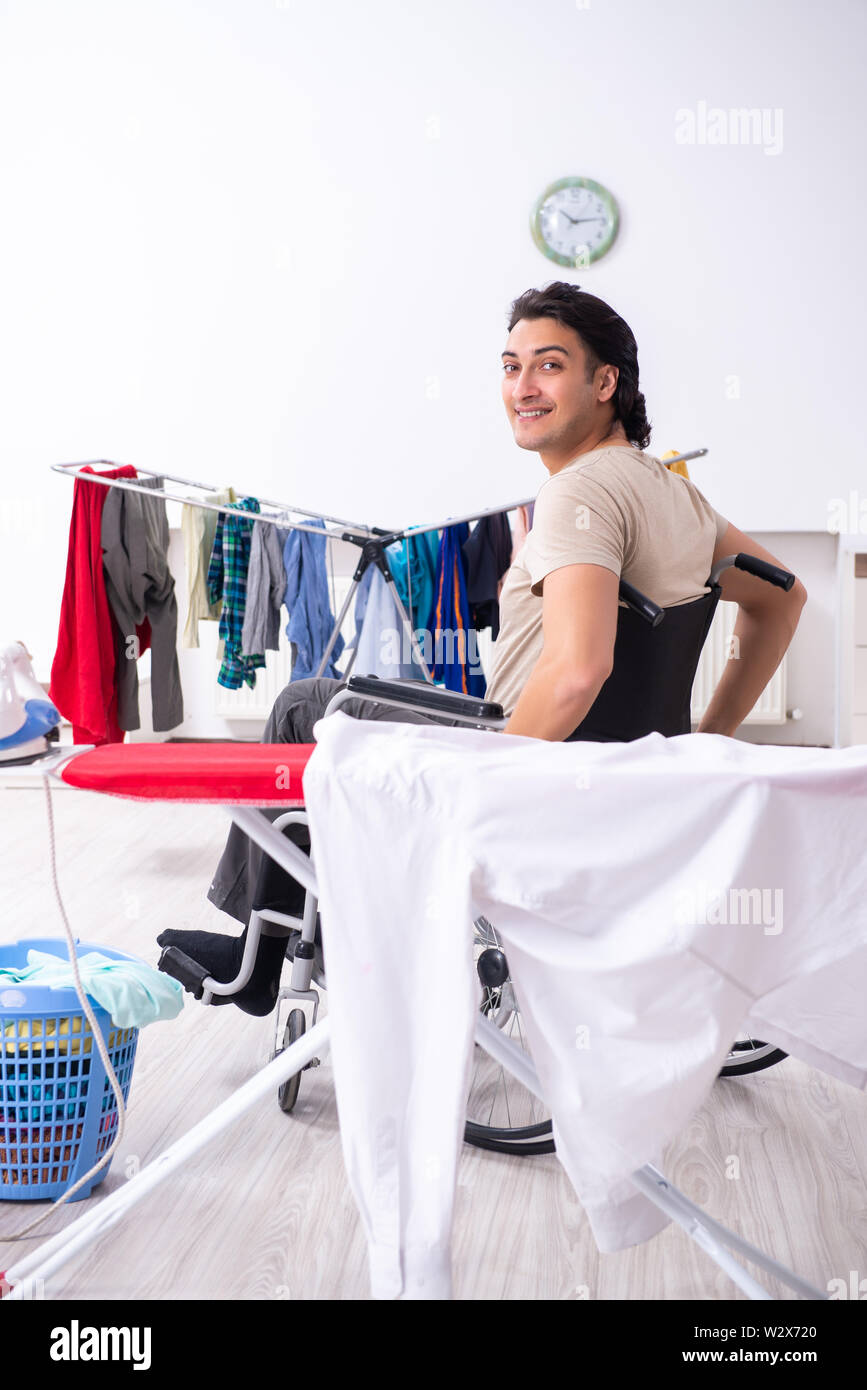 The young man in wheel-chair doing ironing at home Stock Photo - Alamy