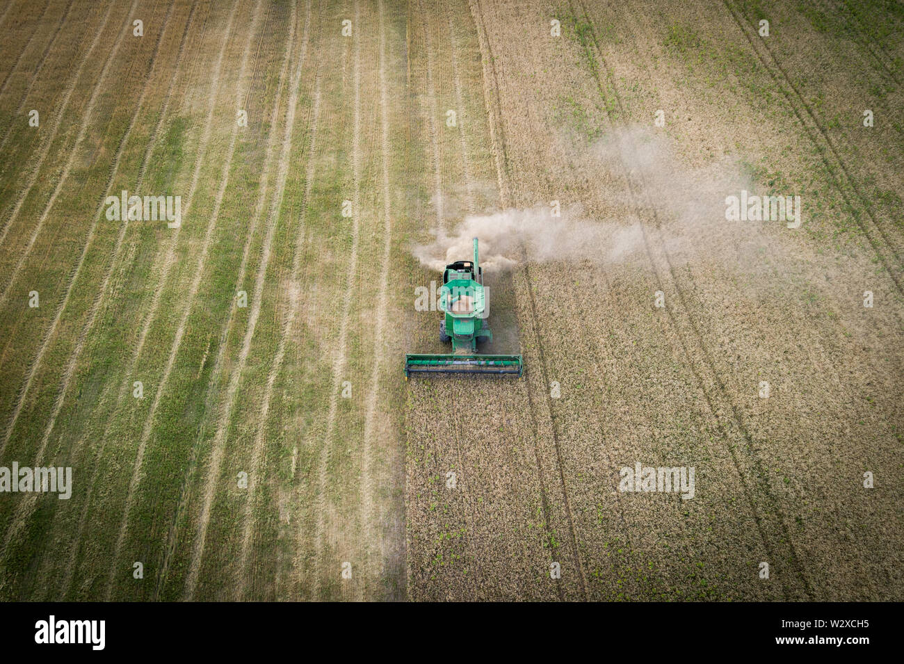 Aerial shot of a combine harvesting triangle peice of crop field on a ...