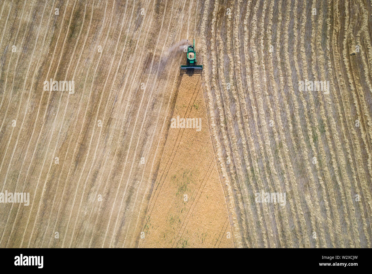 Aerial shot of a combine harvesting triangle peice of crop field on a ...