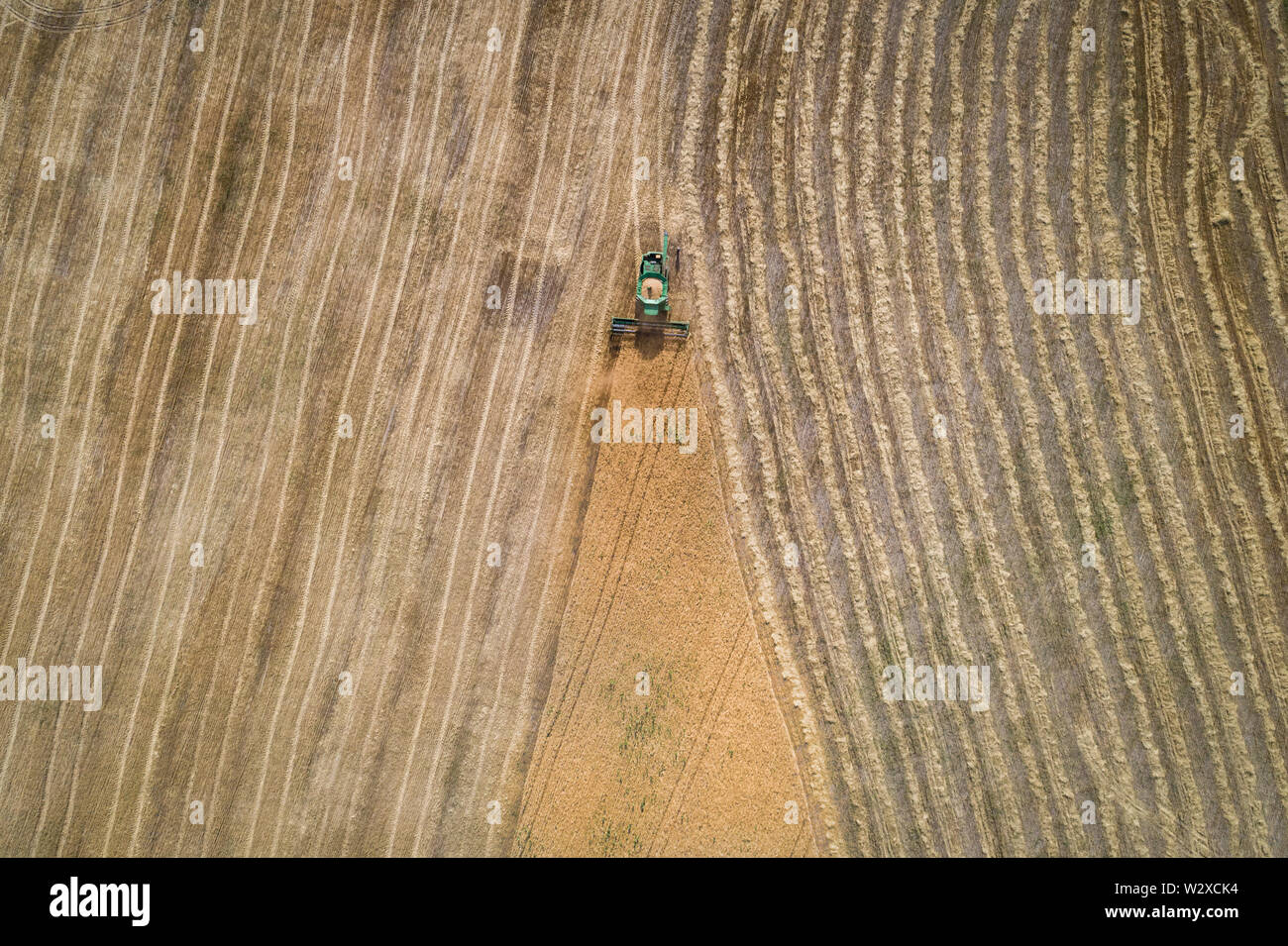 Aerial shot of a combine harvesting triangle peice of crop field on a ...