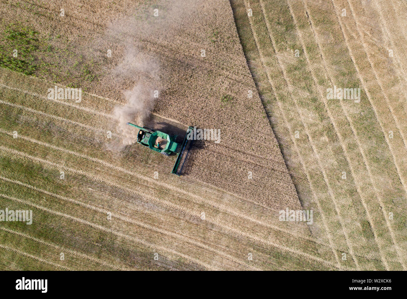 Aerial shot of a combine harvesting triangle peice of crop field on a ...
