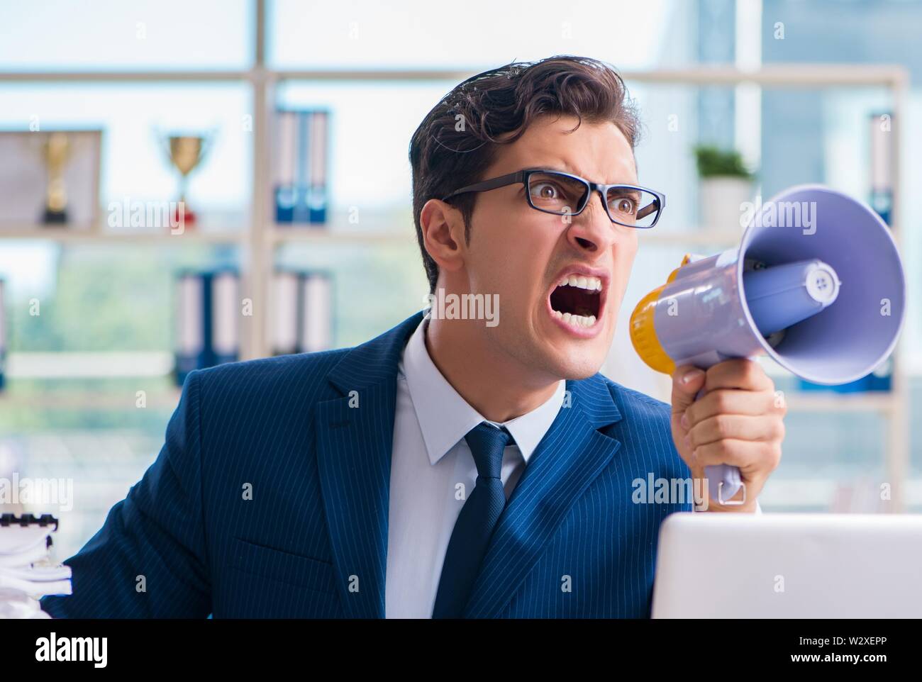 The angry aggressive businessman with bullhorn loudspeaker in office ...