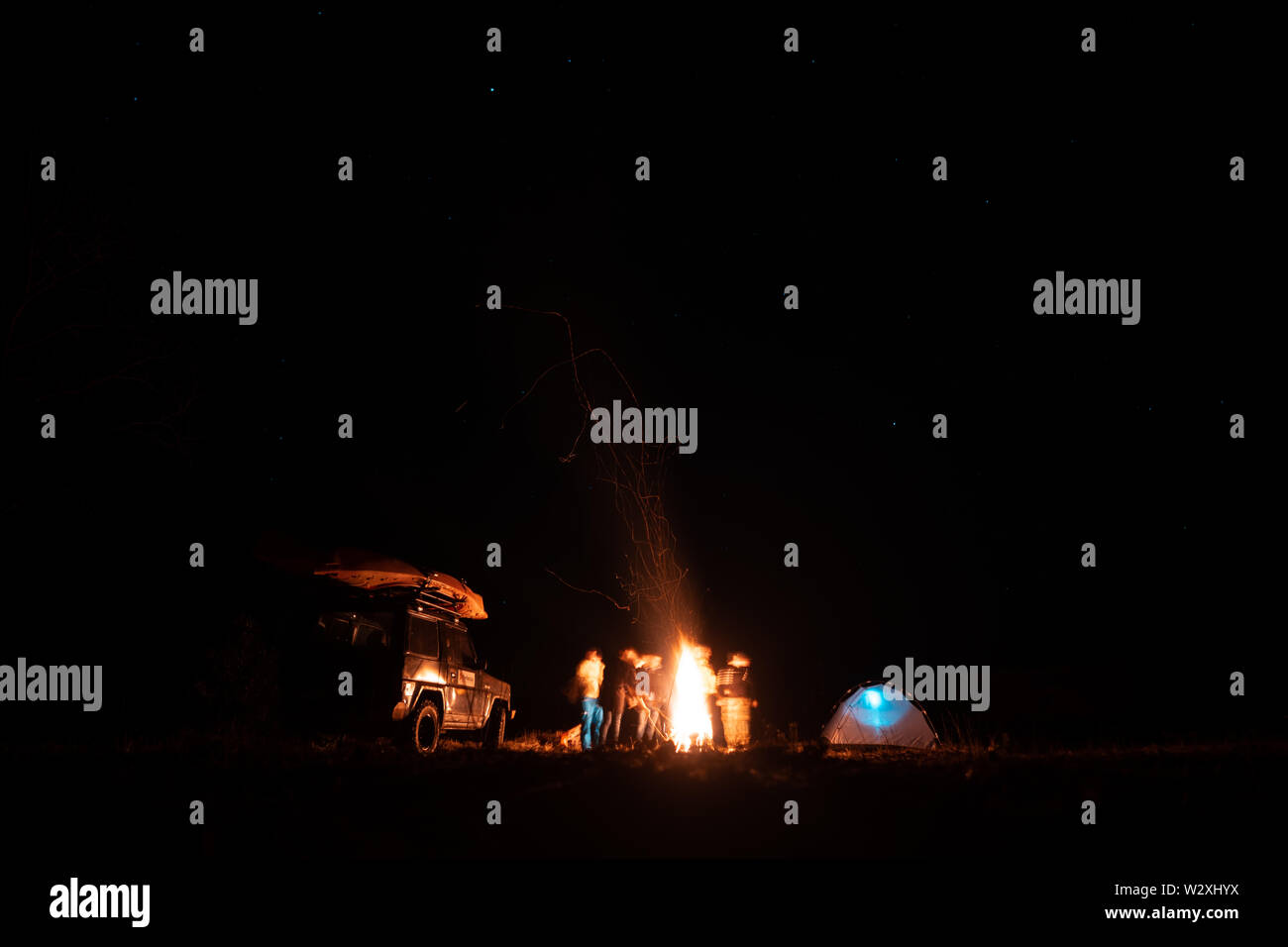Happy Friends having a rest together around campfire Stock Photo - Alamy