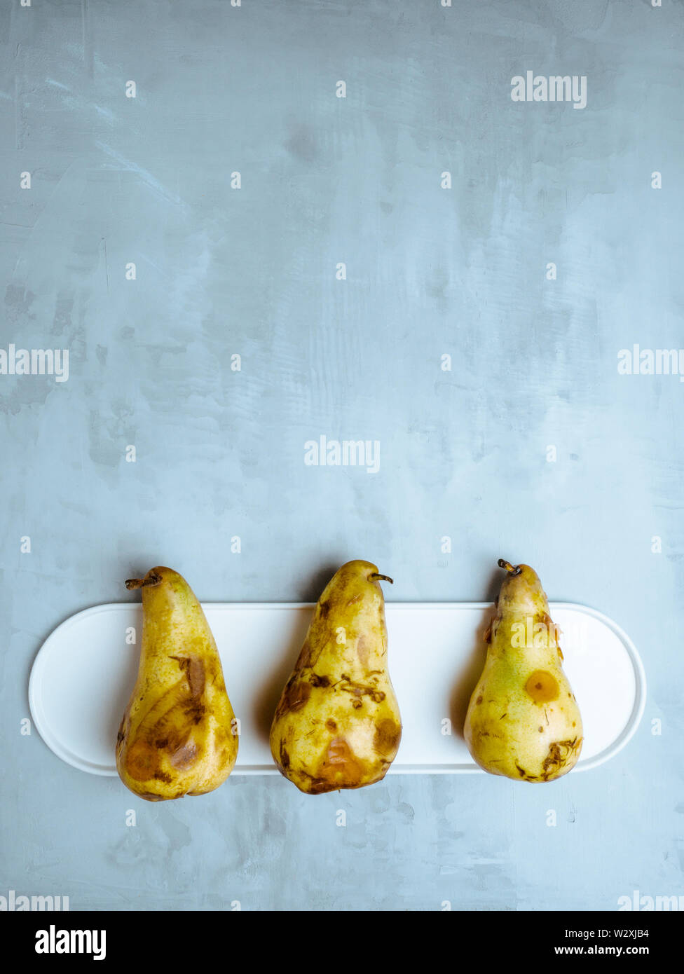 Trendy ugly organic pear on light blue backround. Zero waste concept ...